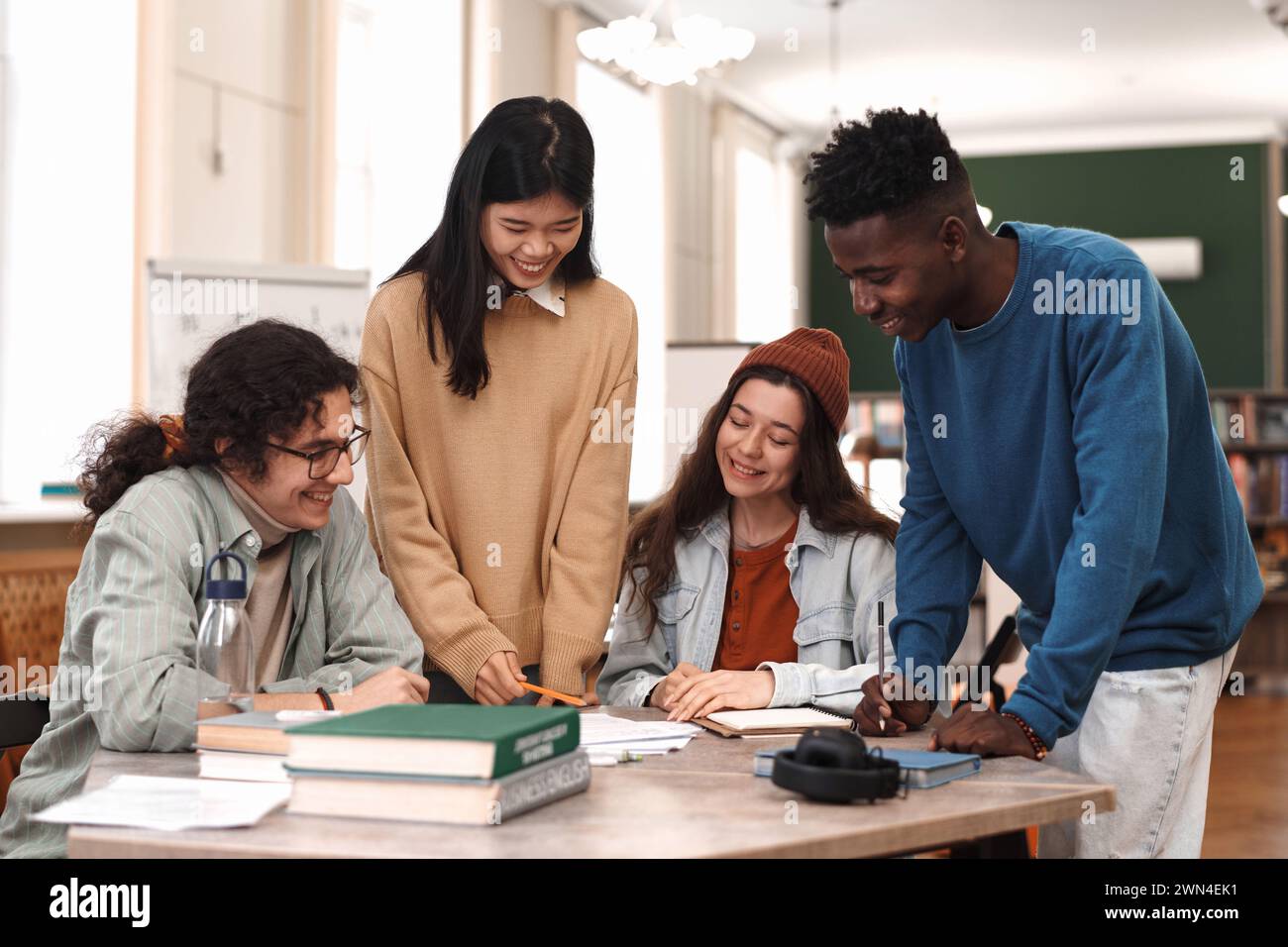 Multiethnic group of students studying together around table in ...