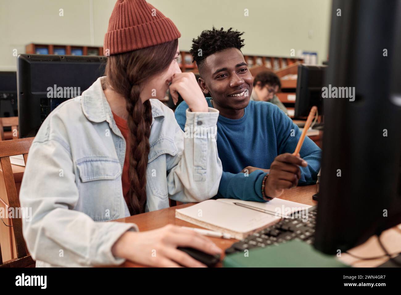 Portrait of two young students using computer in college library and ...
