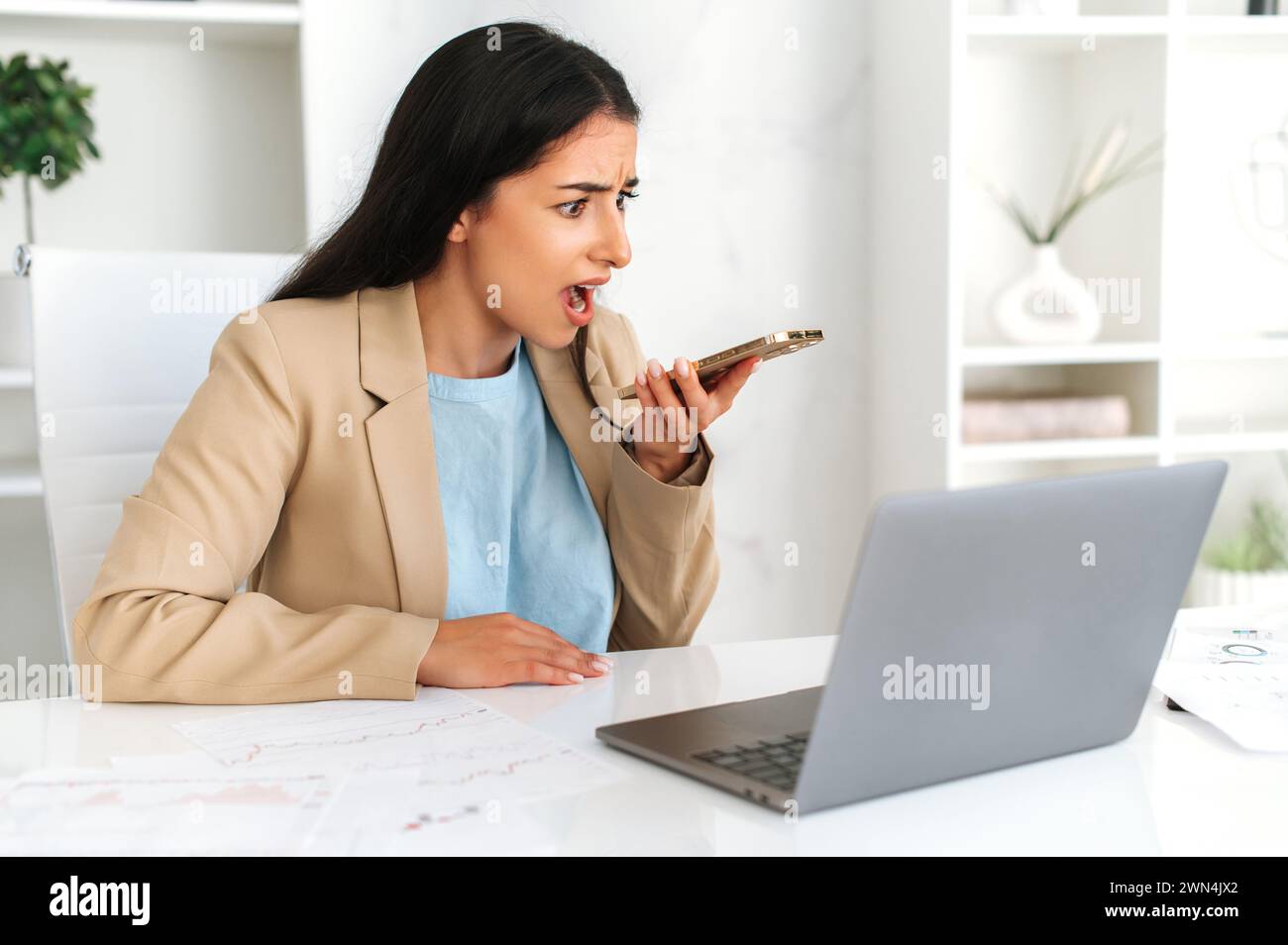 Speakerphone concept. Annoyed angry young woman of indian or arabian ...