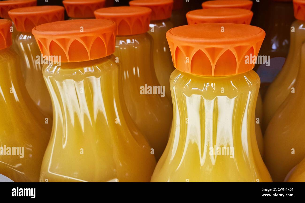 Orange juice bottles on a supermarket shelf with focus on foreground ...