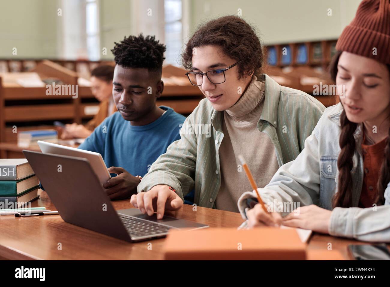 Diverse group of three young people using laptop computer together in ...