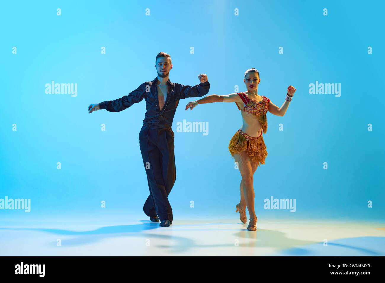 Young man and woman in elegant stage costumes performing samba, dancing ...