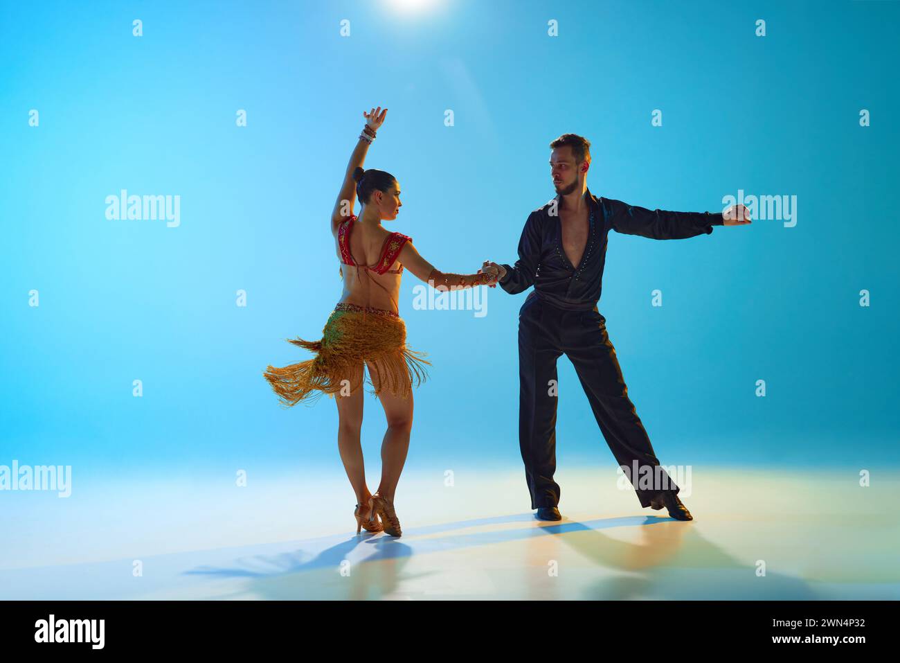 Beautiful young man and woman in elegant stage costumes dancing Latin ...