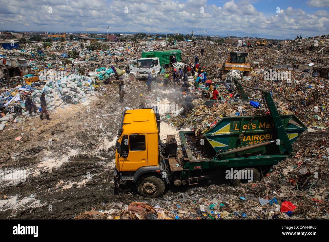 Waste collectors offloading waste products from a garbage truck at the ...