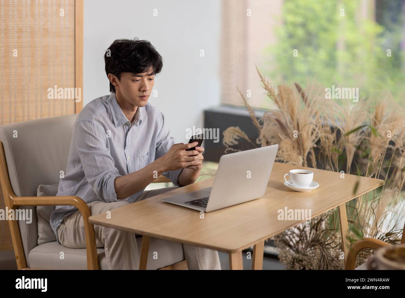 Young Chinese man using smartphone in café Stock Photo - Alamy