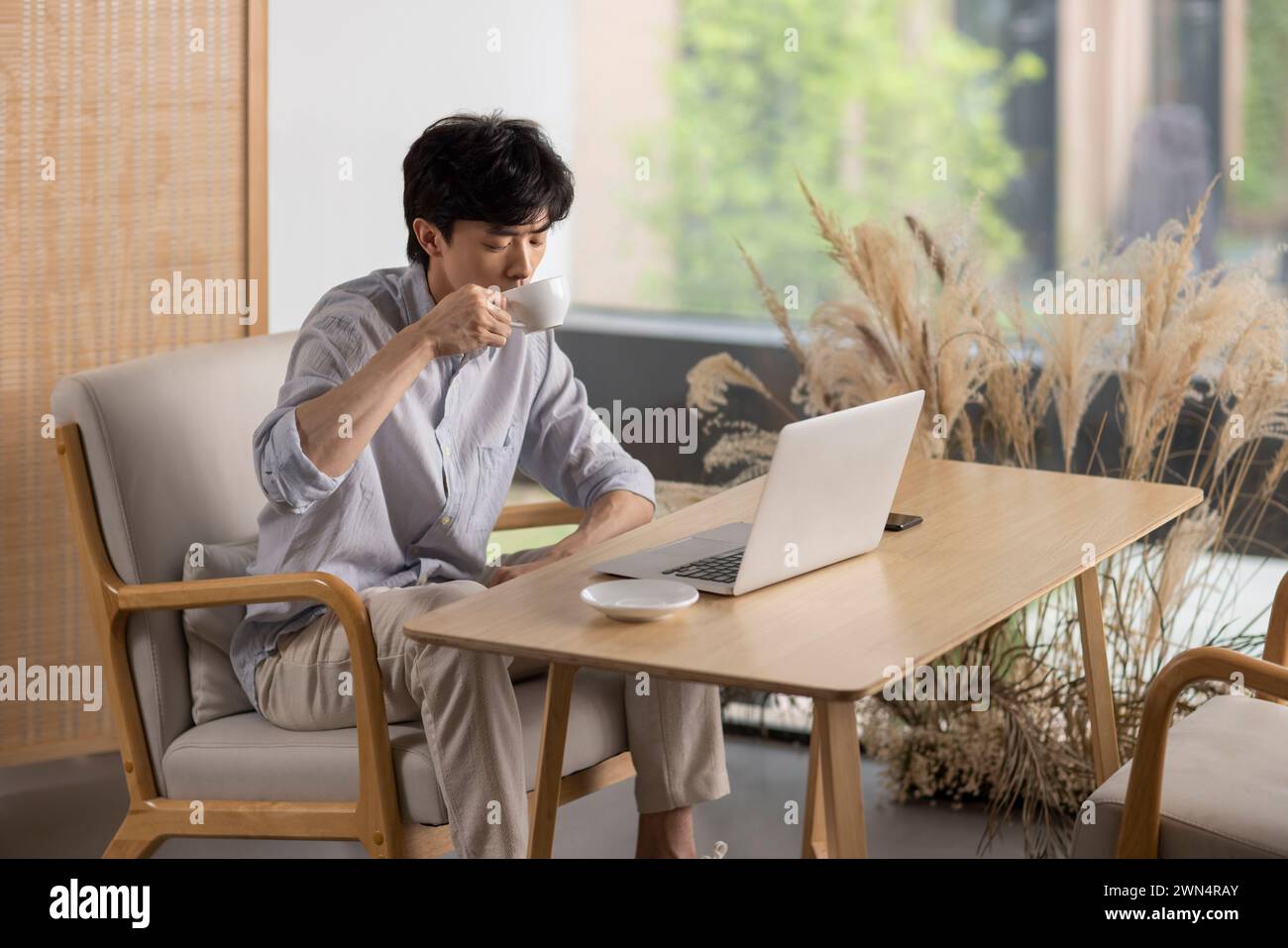 Young Chinese man drinking coffee in café Stock Photo - Alamy