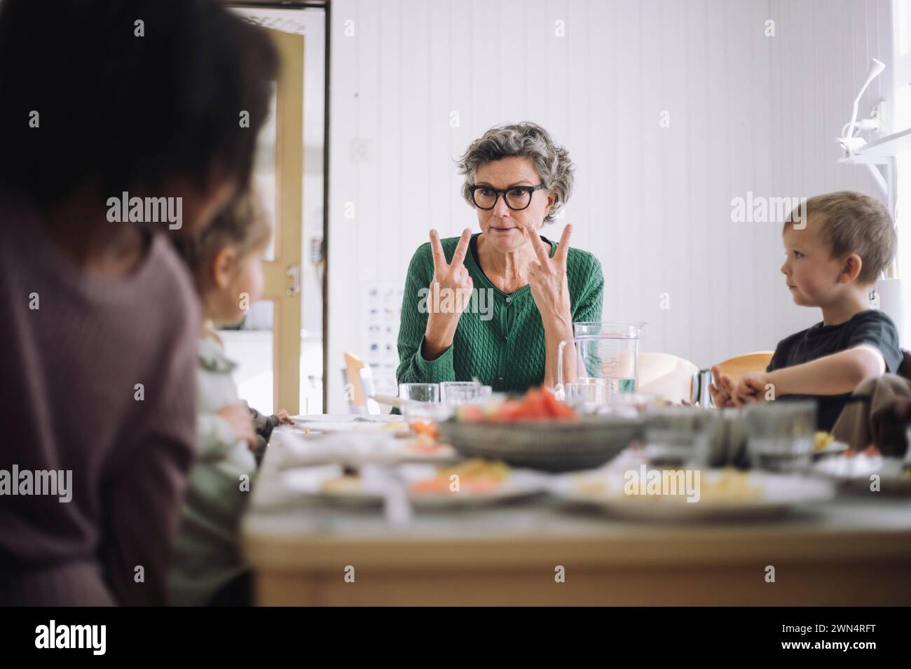 Senior female teacher communicating with students through hand signs ...