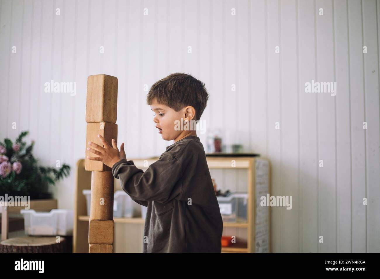 Side view of boy stacking toy blocks while playing in classroom at ...