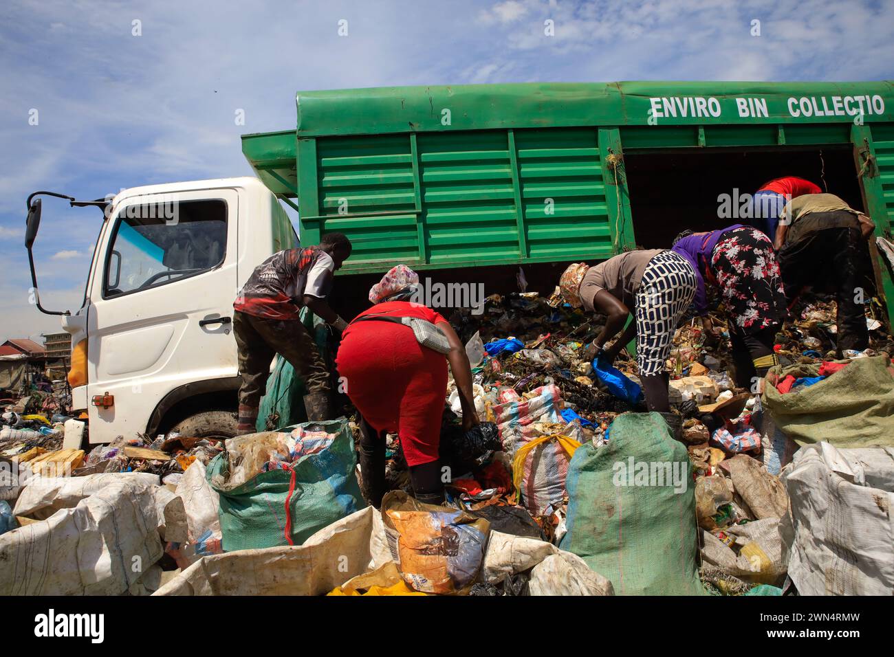 Waste collectors offloading waste products from a garbage truck at the dumpsite. Dandora slum ...