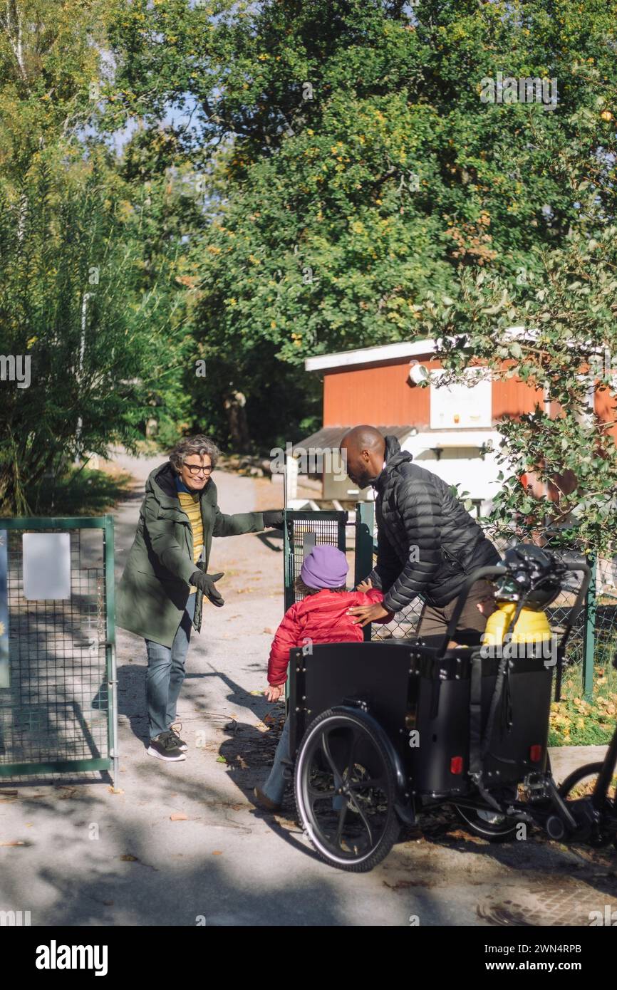 Female teacher assisting children while entering at kindergarten Stock ...