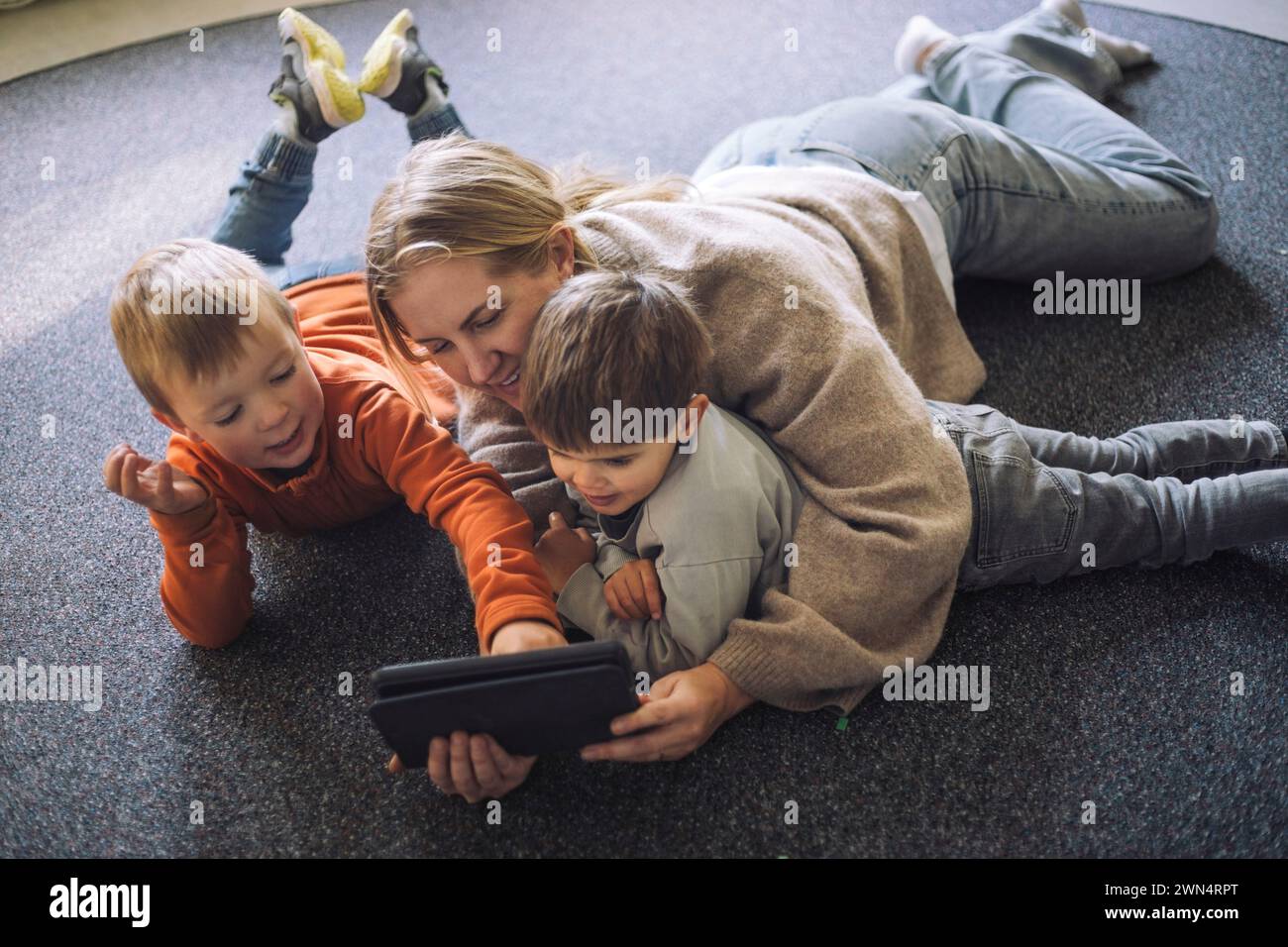 High angle view of kids watching digital tablet with female teacher ...
