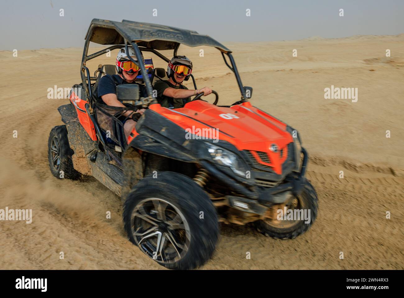 wheels spin and sand flies as a dune buggy corners at speed in the ...