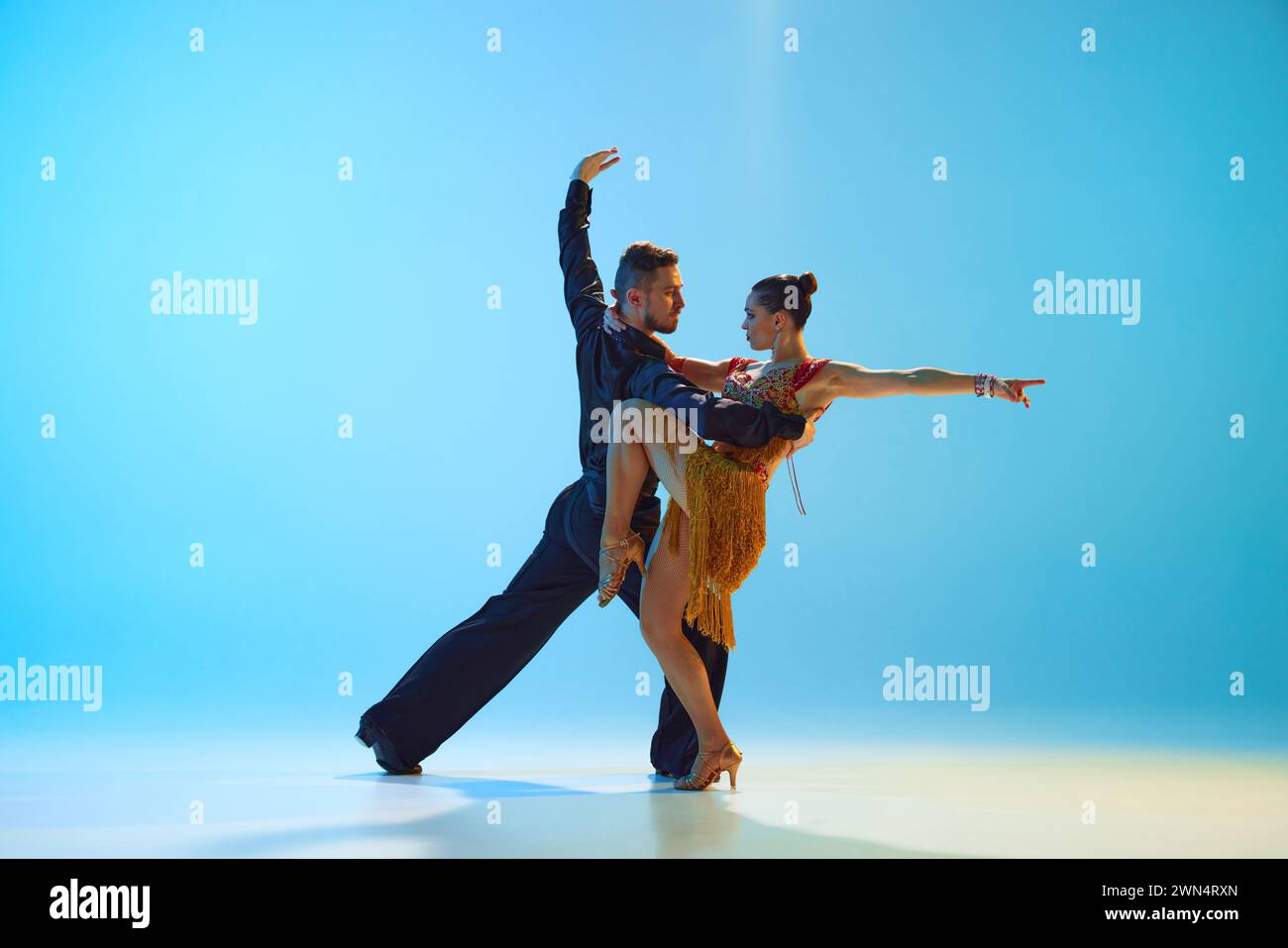 Young man and woman in elegant stage costumes performing samba, dancing ...
