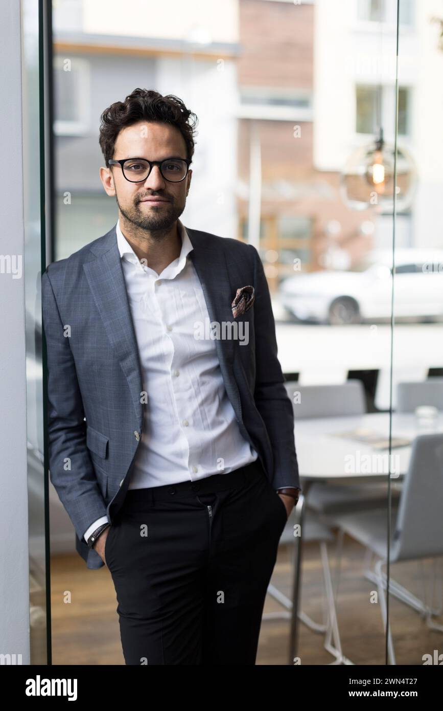 Portrait of confident male real estate agent standing with hands in ...
