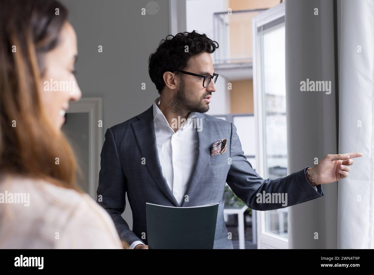 Male real estate agent pointing while talking with female client at ...