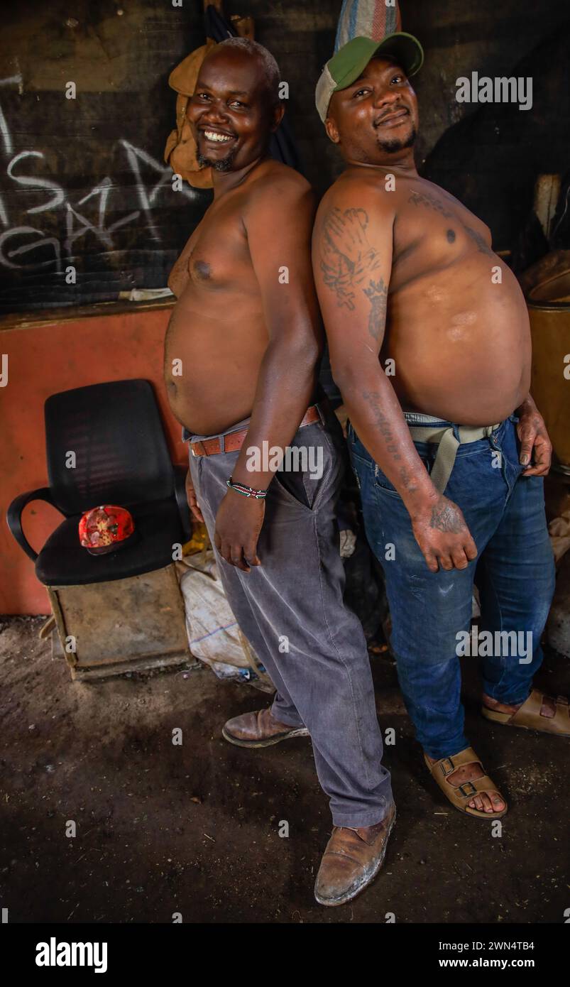 Two shirtless men pose for a photo at the dumpsite. Dandora slum lays ...