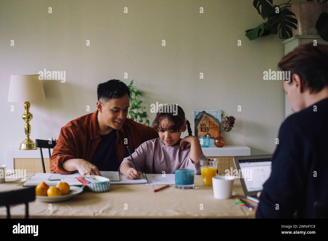 Gay father assisting daughter while doing homework at home Stock Photo - Alamy