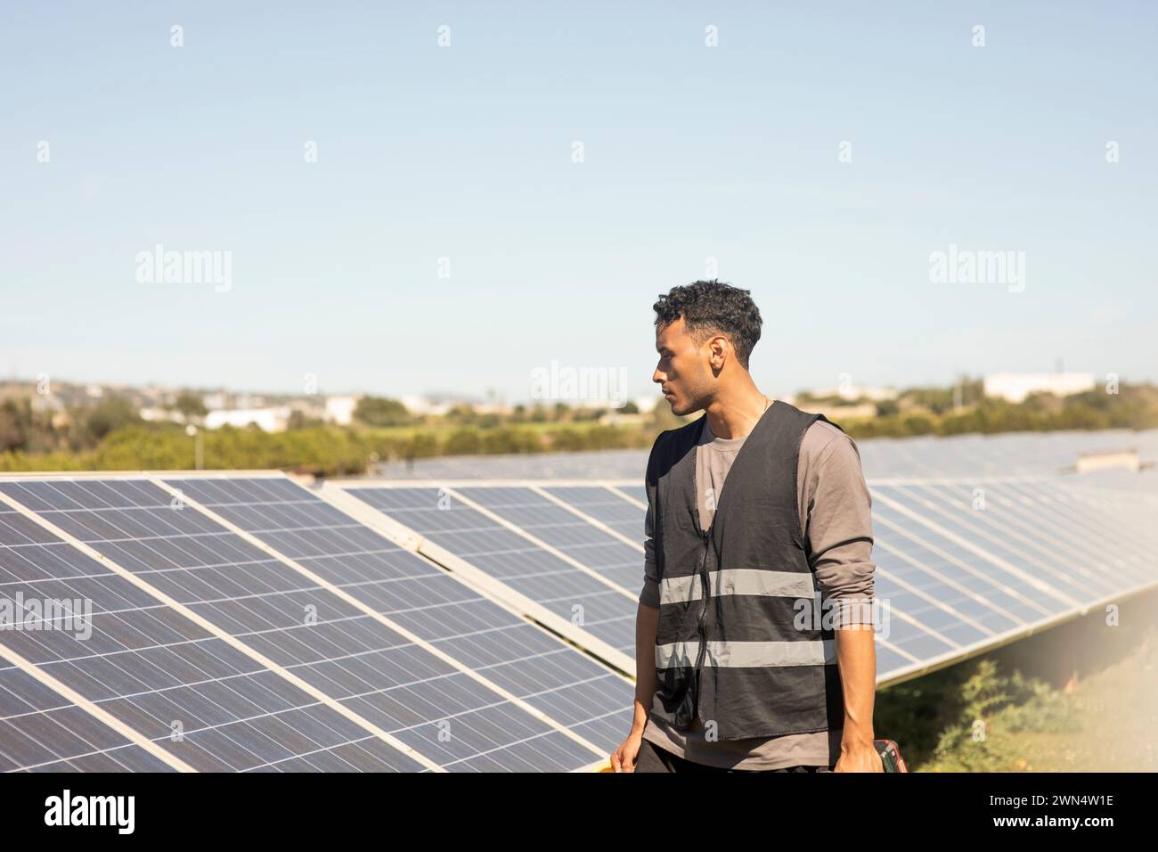Young male engineer wearing reflective jacket while looking at solar ...