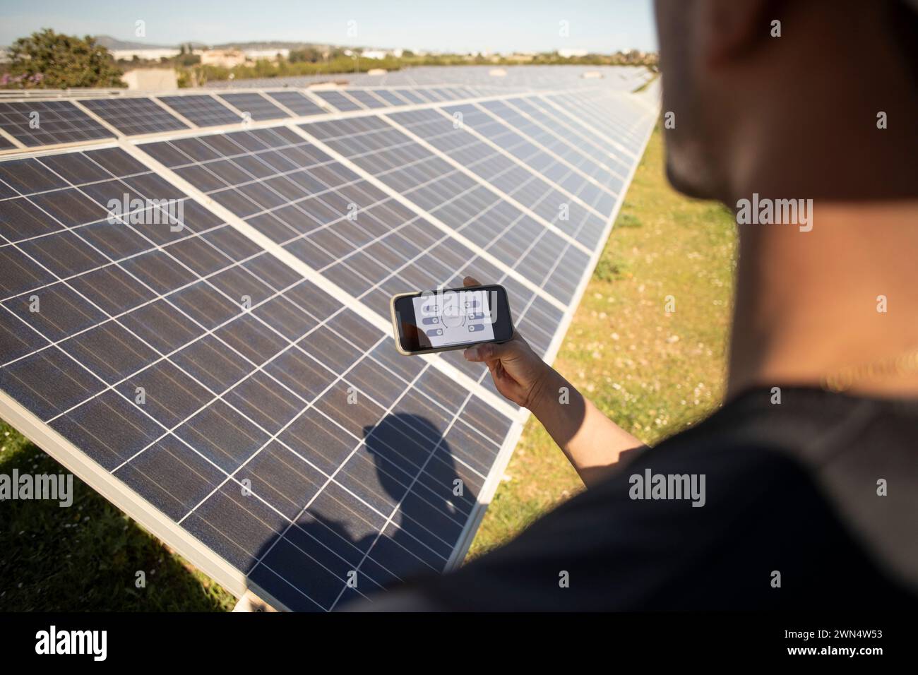 Male engineer programming solar panels through smart phone app at power ...