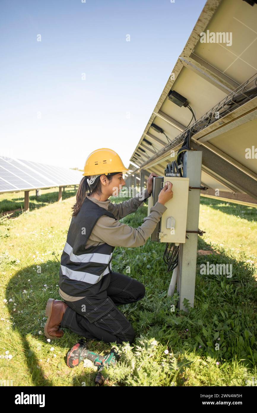 Side view of female engineer repairing fuse box while kneeling near ...