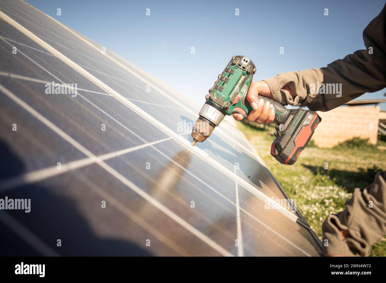 Hand of female engineer installing solar panels with drill while ...