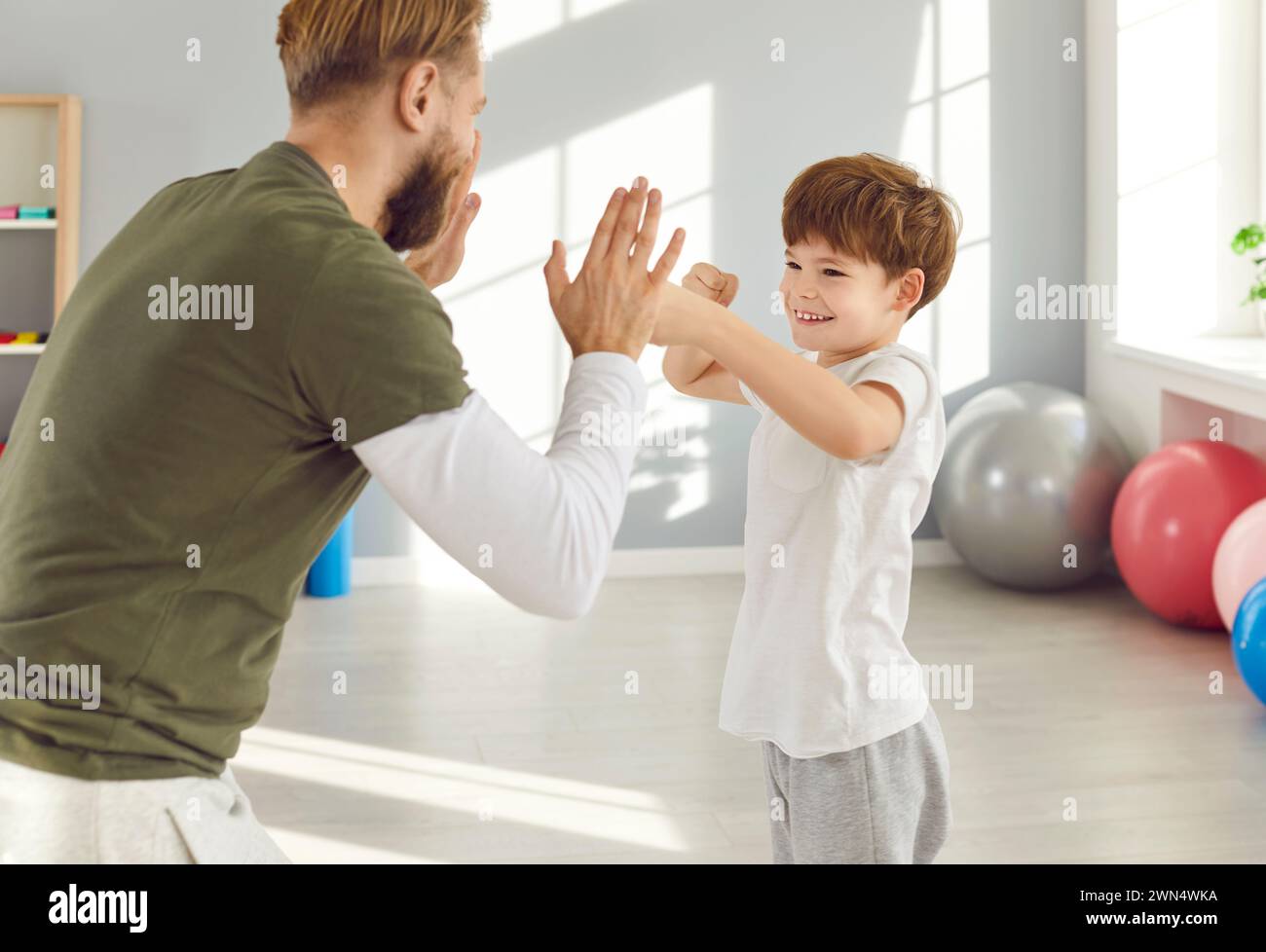 Family sport, father and young son boxing, fighting with fists, healthy ...