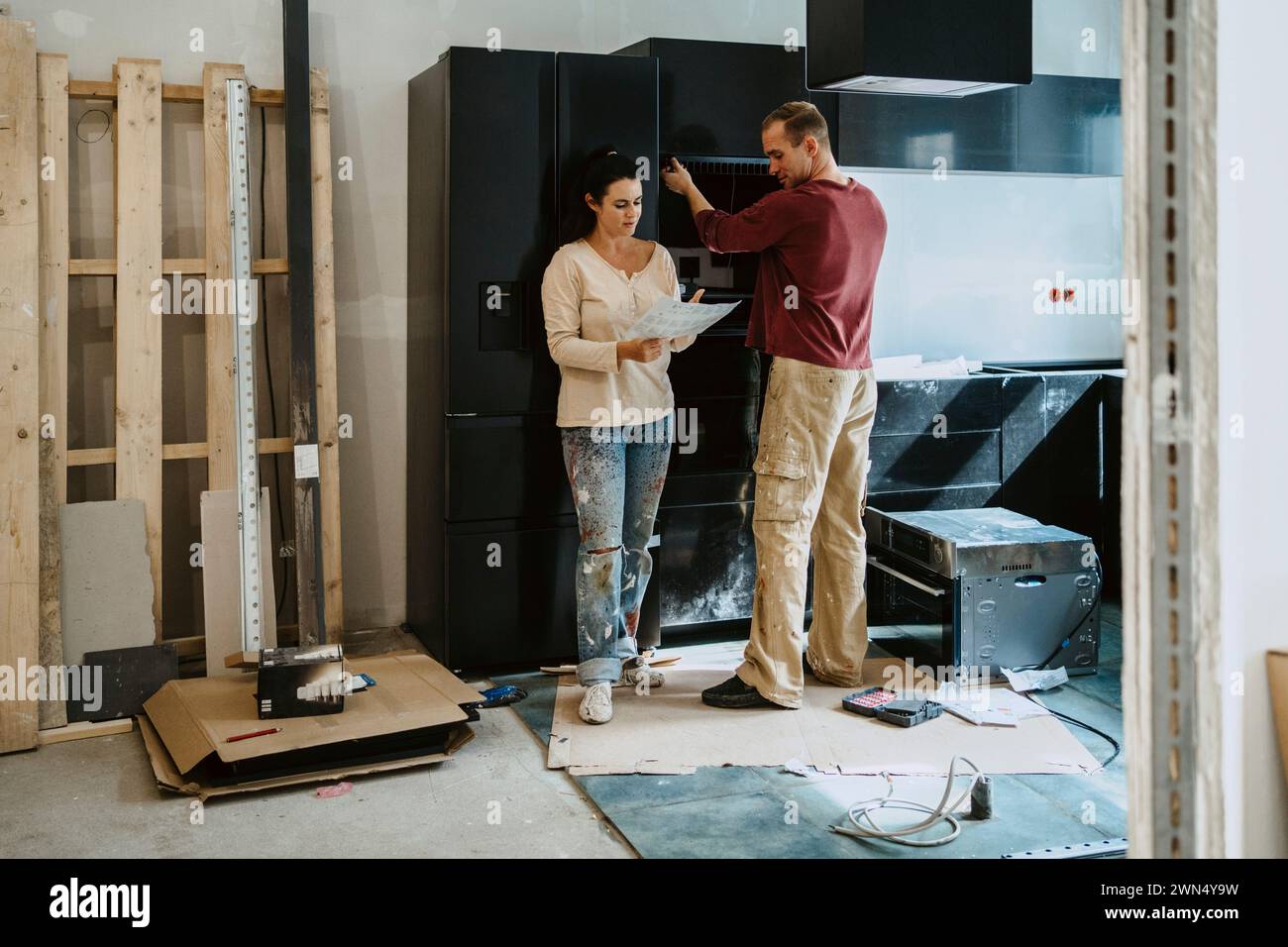Couple discussing over document while fixing cabinet together in ...