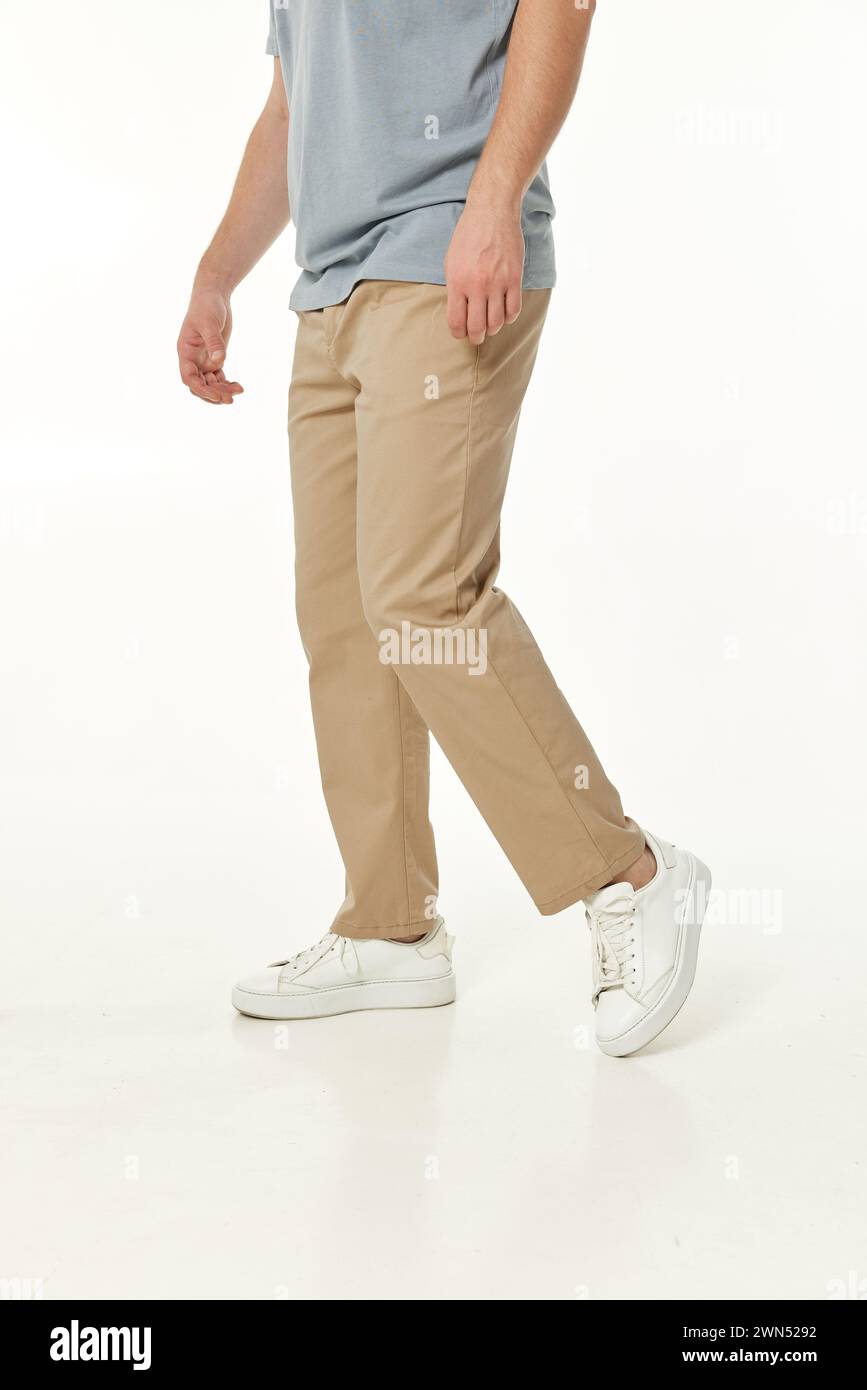 man wearing white sneakers and casual beige pants on studio background ...