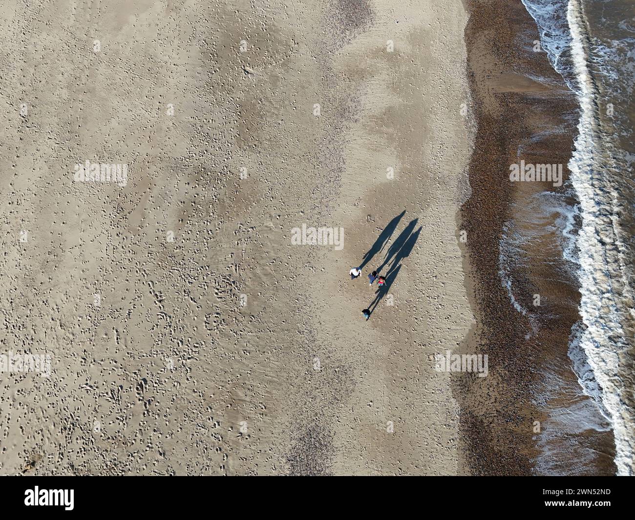 Overhead birds eye drone aerial view people walking on beach long ...