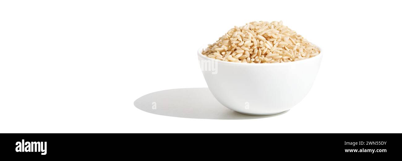 A bowl of uncooked brown rice, isolated against a white background ...