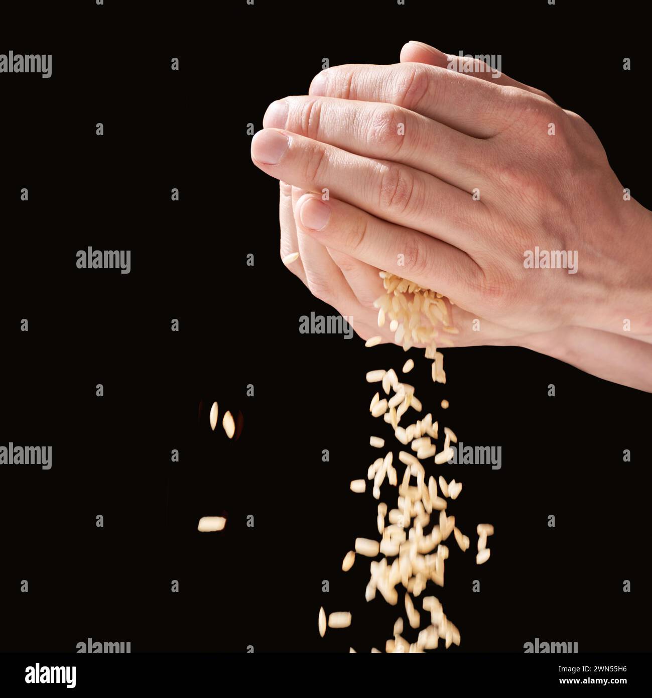 A hands hold a pile of rice, symbolizing charity, love, and hope. With ...