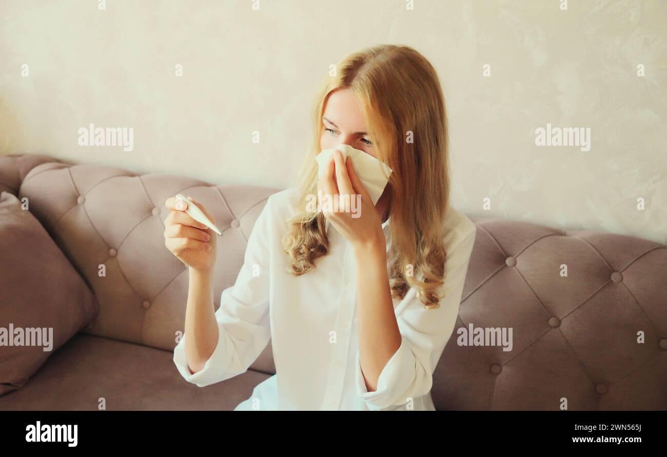 Sick exhausted woman sneezing blow nose using tissue and measuring ...