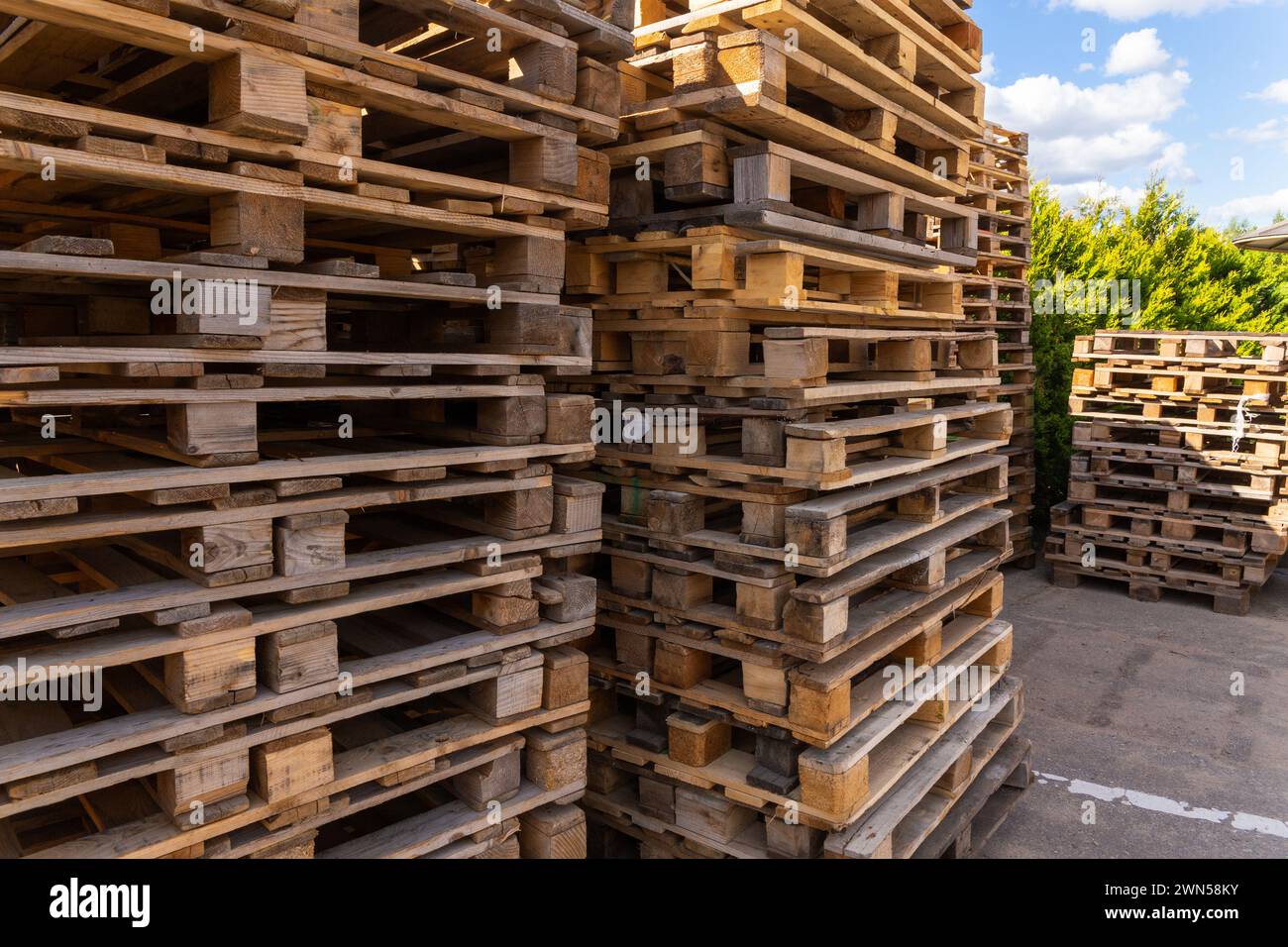 Piles of stacked natural wooden shipping pallets. Outside a big stack with big stack of wooden ...