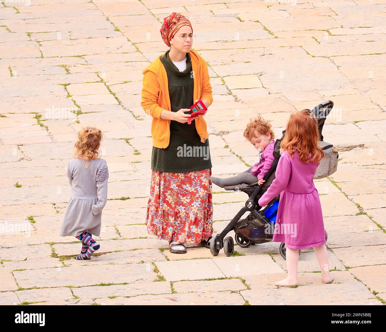 A young Jewish mother and three daughters hers on a pavement in the Old ...