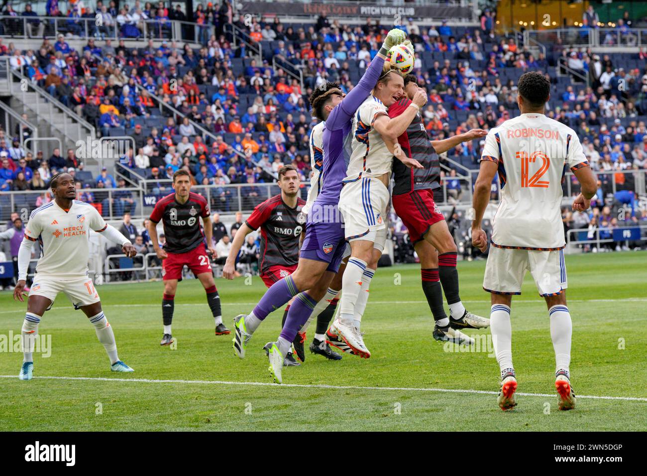 FC Cincinnati goalkeeper Roman Celentano, left, clears the ball as ...