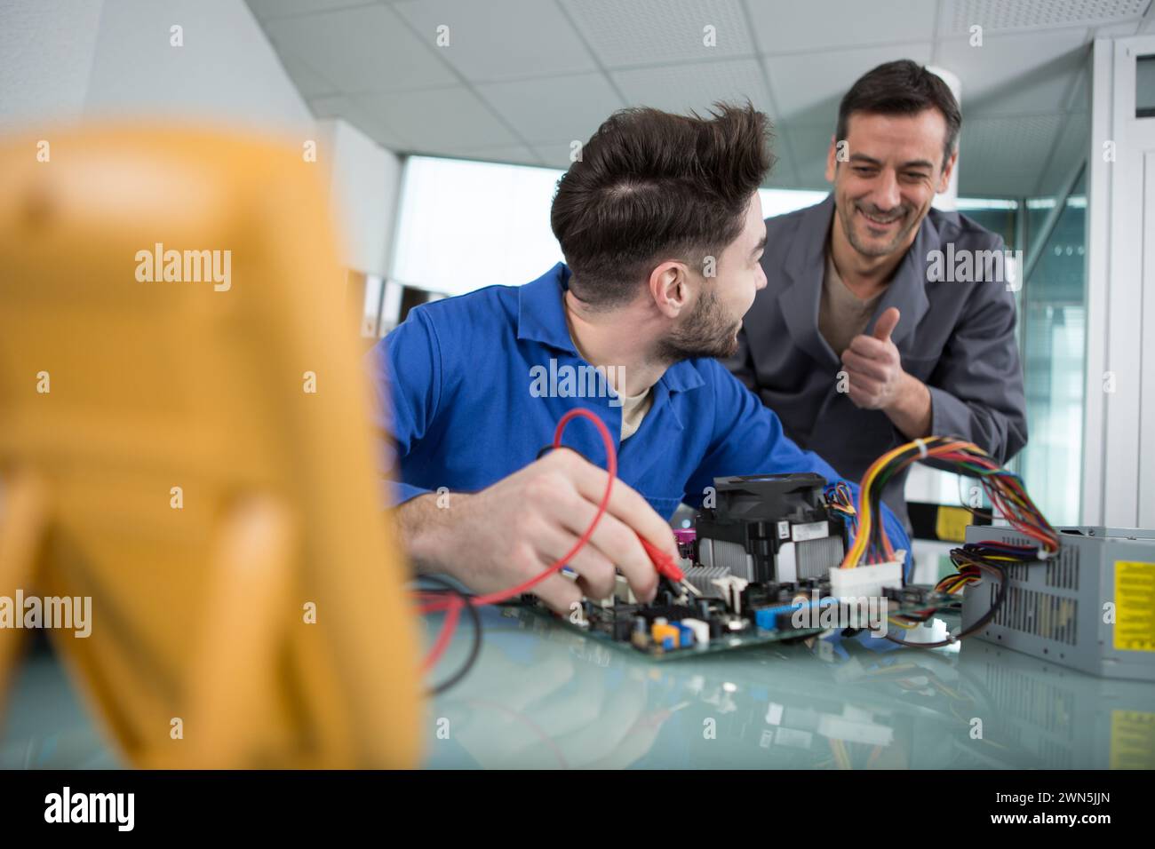 boss giving thumbs up to apprentice technician using multimeter Stock ...