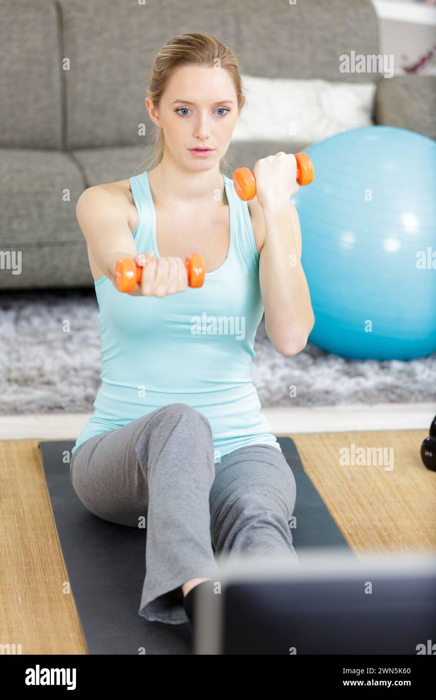 beautiful woman doing exercise with dumbbells while watching tv Stock ...