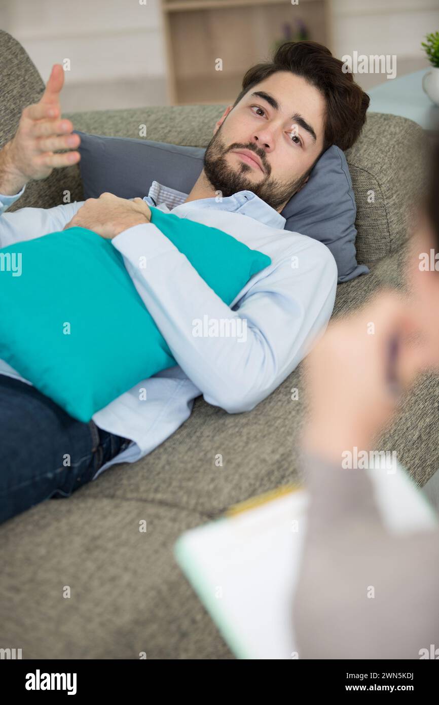 sad man laying on a couch in the living room Stock Photo - Alamy