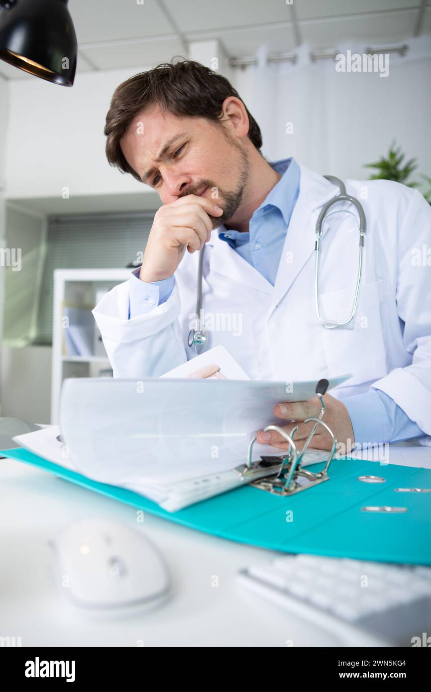 male doctor in surgery reading patient notes Stock Photo - Alamy