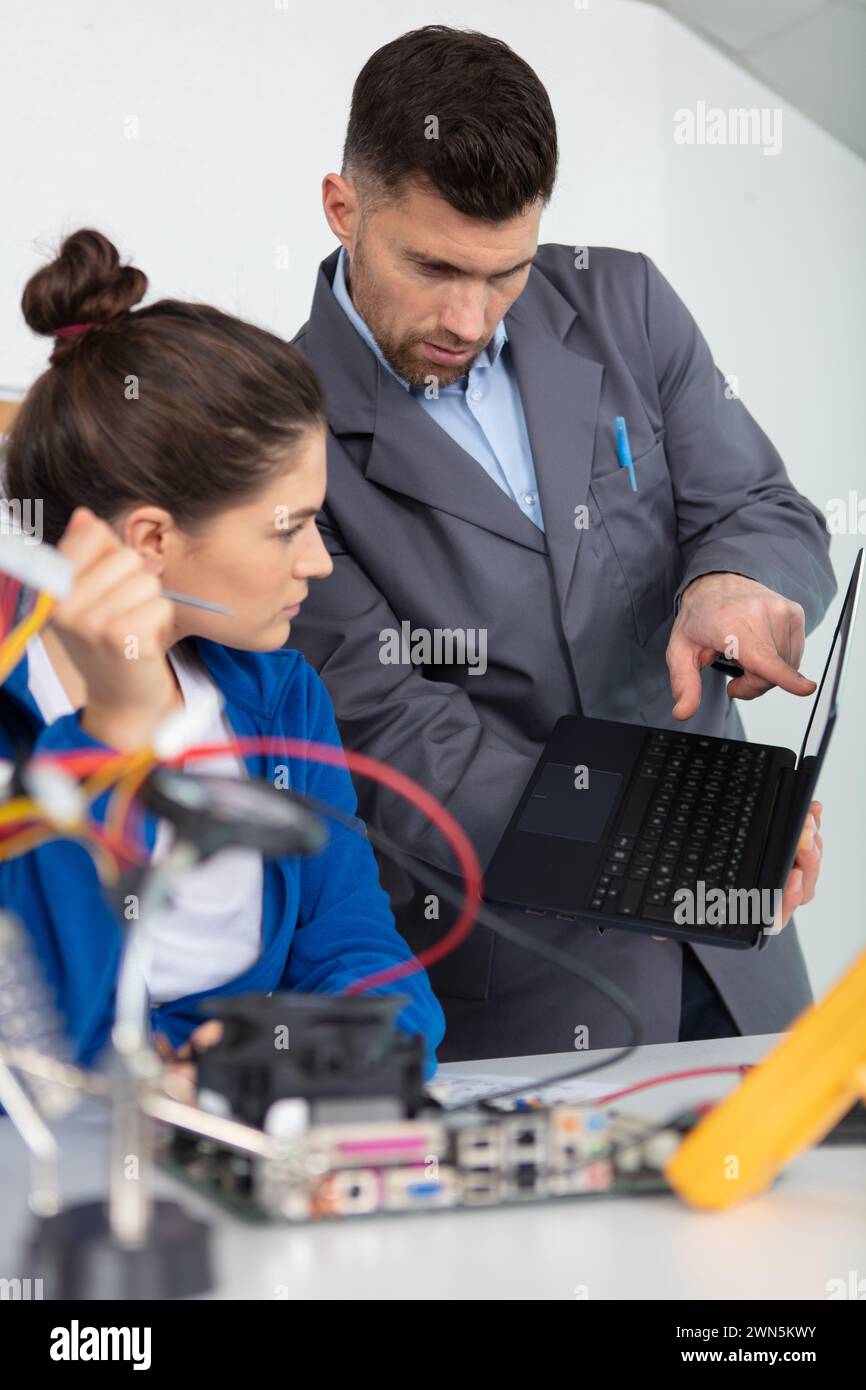 female apprentice repairing computer with the help of teacher Stock ...