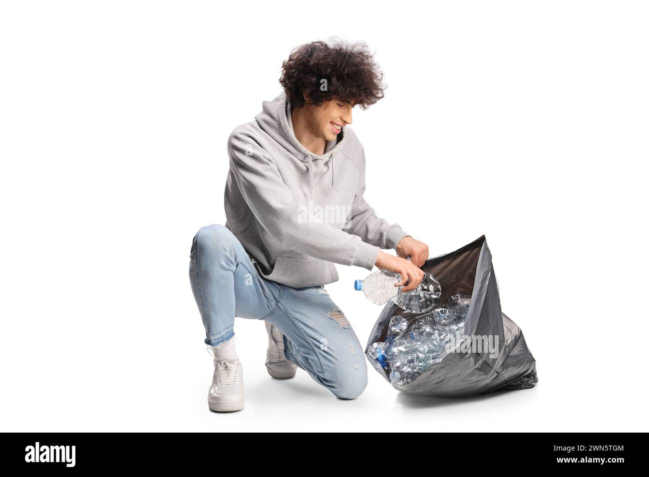 Young man collecting plastic bottles in a black waste bag isolated on ...