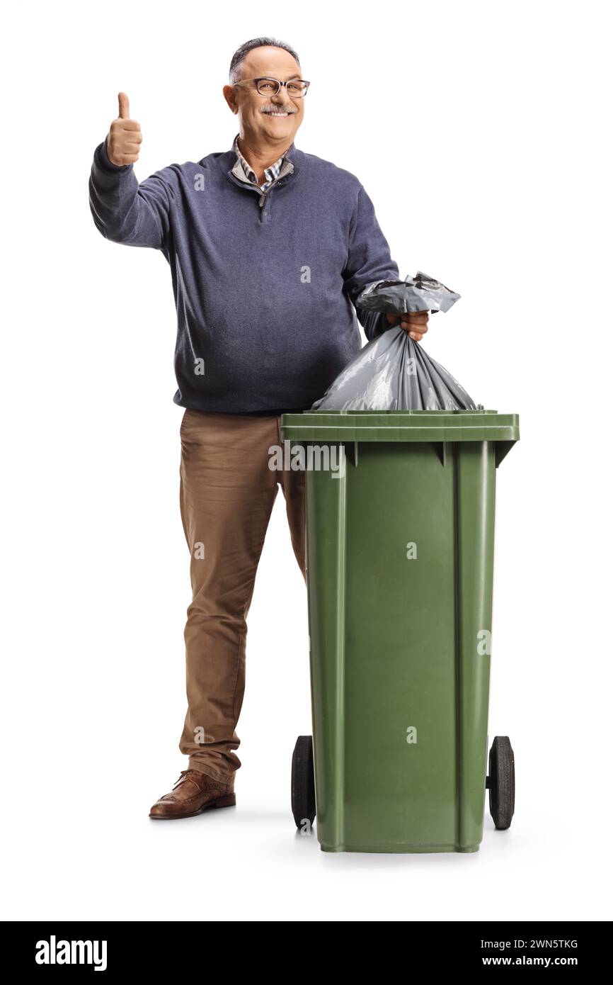 Smiling mature man throwing a waste bag in a dustbin and gesturing ...