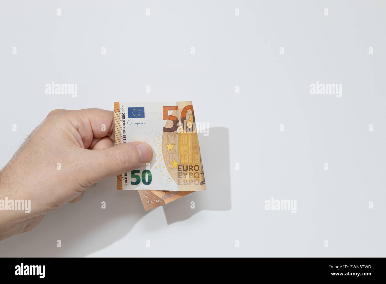 Hand holding a fifty euro banknote on white background. Copy space ...