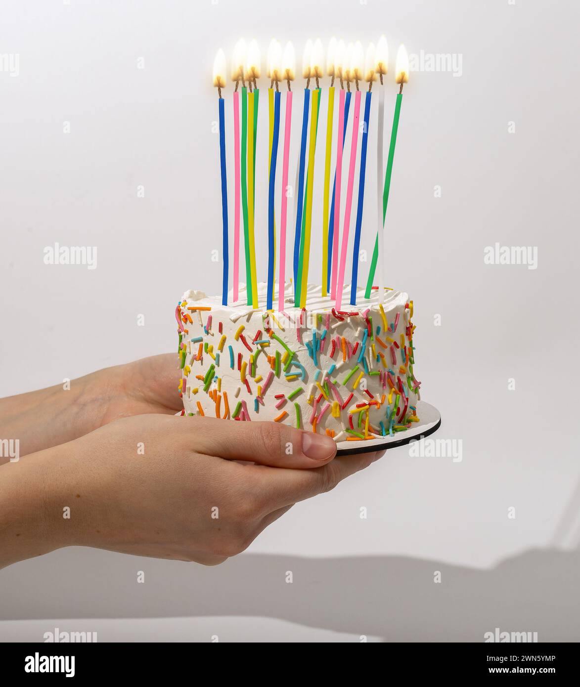 Hands giving birthday cake with many tall candles Stock Photo - Alamy