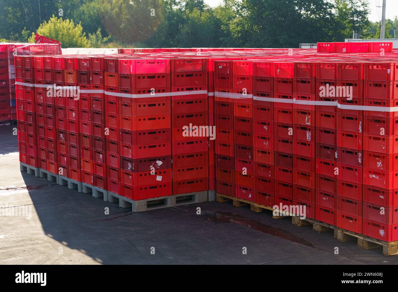 A cluster of numerous red boxes stacked high in a crowded parking lot ...