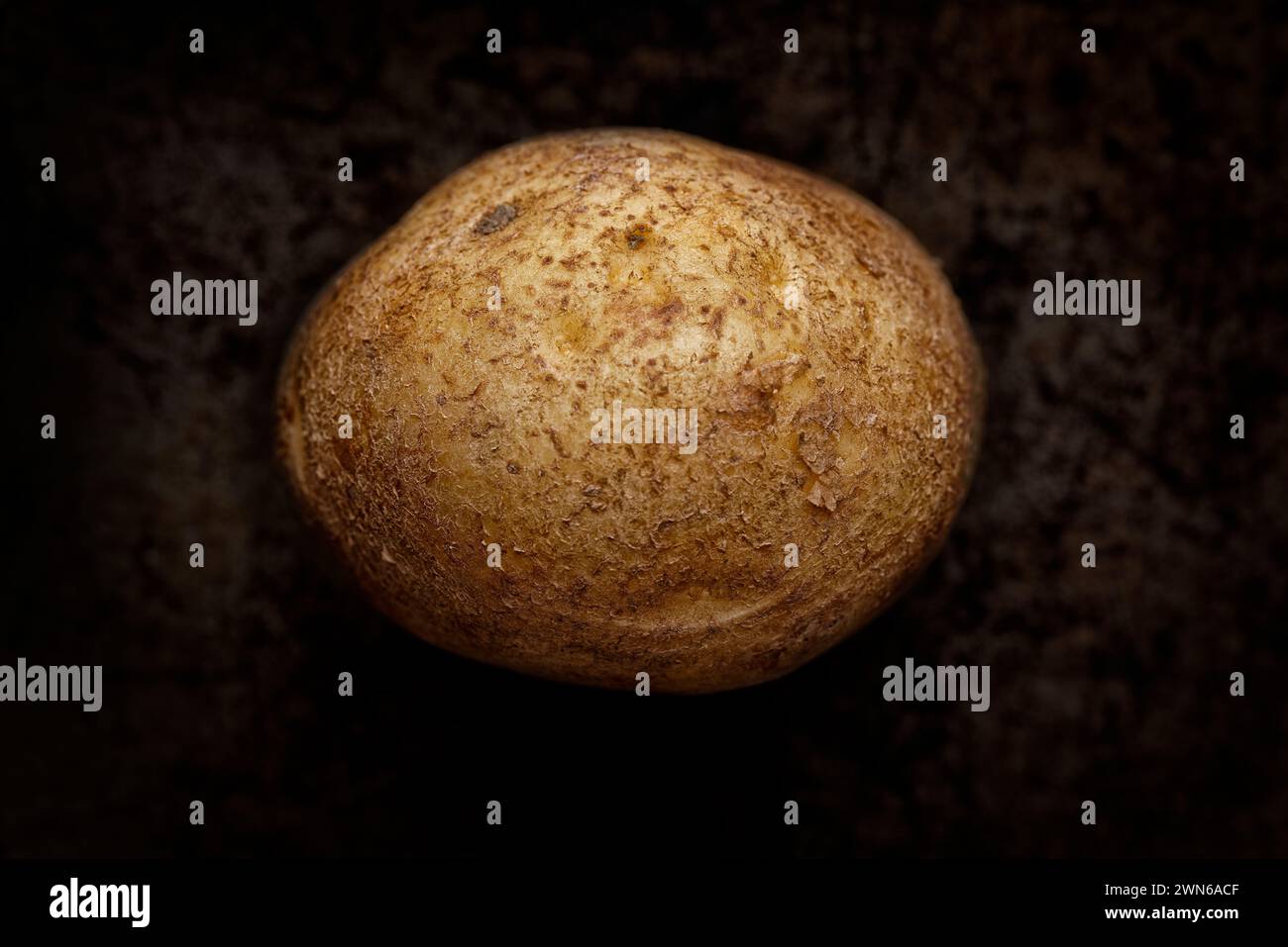 A close-up of a textured potato on a black background Stock Photo - Alamy