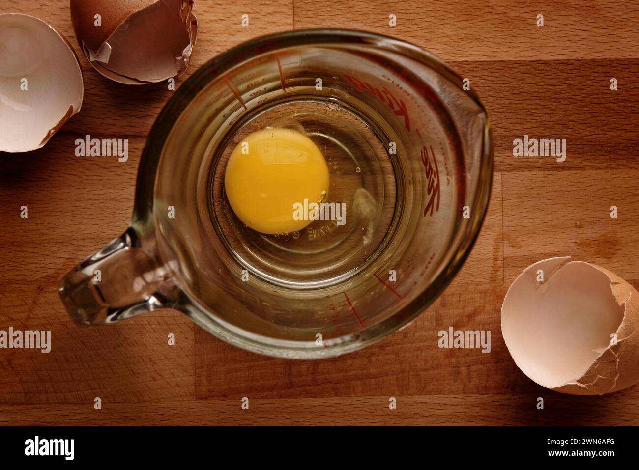 A top view of a glass beaker on a table with an egg next to cracked ...