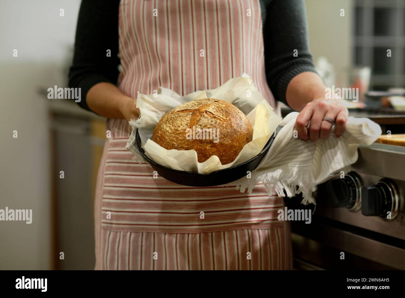 A chef wearing an apron holding a tray with artisan bread Stock Photo ...
