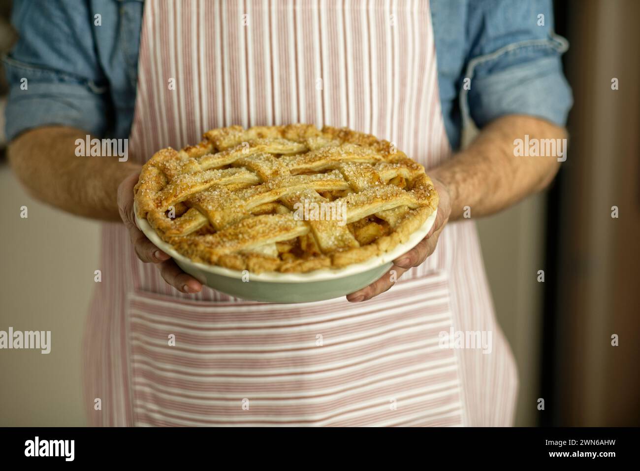 A chef in an apron holding a plate with delicious apple pie Stock Photo ...