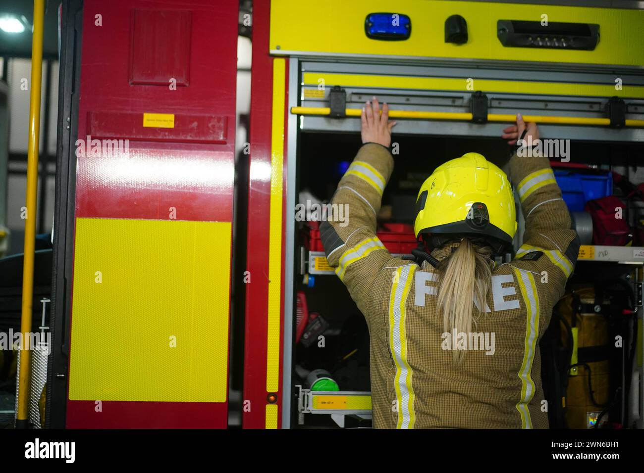A female firefighter prepares equipment on a fire engine during a ...
